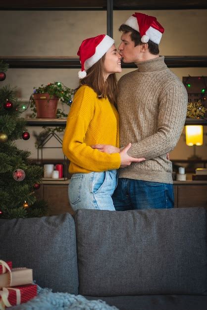 Free Photo Christmas Couple Wearing Santa Hats Kissing