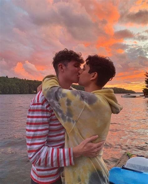 Two People Kissing Each Other In Front Of A Body Of Water