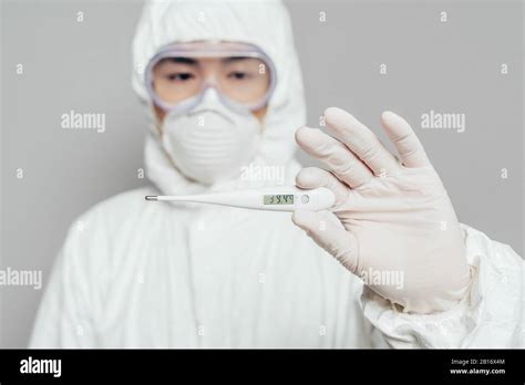 Selective Focus Of Asian Epidemiologist Holding Thermometer Showing
