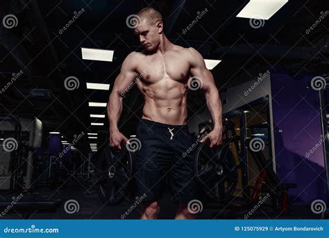 Handsome Strong Athletic Man Pumping Up Muscles With Dumbbells