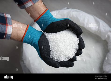 Farmer Holding Pile Of Ammonium Nitrate Pellets Over Bag Top View