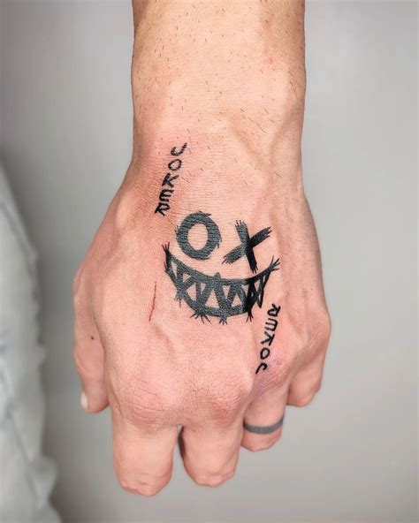 A Person S Hand With A Smiley Face Tattooed On The Left Side Of His Arm