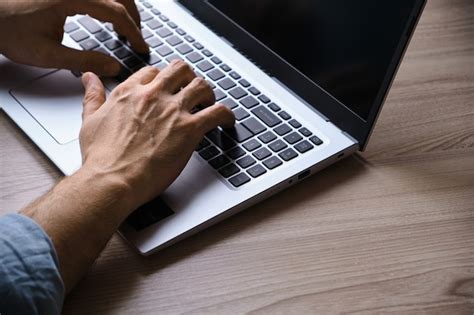 Mãos de homem digitando no teclado do laptop Foto Premium