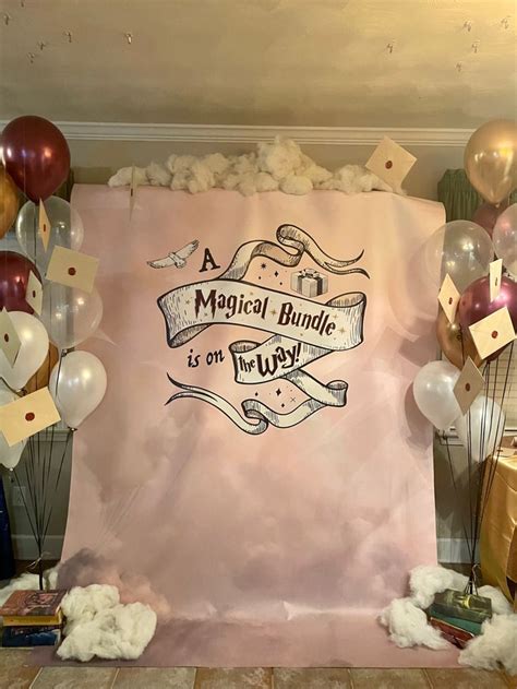 A Pink Backdrop With Balloons And Streamers In The Shape Of Letters
