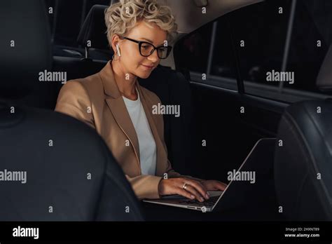 Stylish Business Woman Working On Laptop While Sitting On Back Seat Of