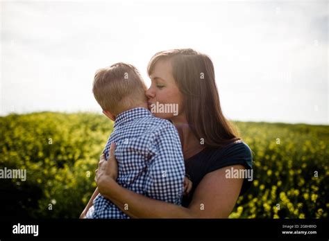 Mother Kissing Son In Wildflower Field Stock Photo Alamy
