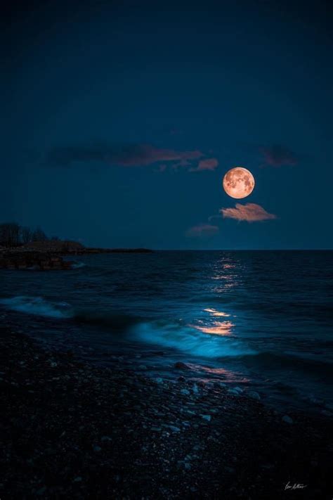 The Full Moon Is Setting Over The Ocean