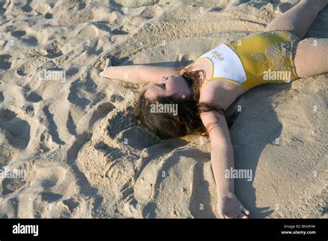Jeune fille allongée sur le dos sur la plage ce qui rend le sable