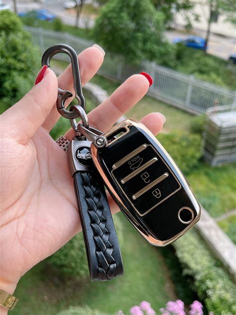 A Hand Holding A Car Keychain With A Cell Phone Attached To The Key Chain
