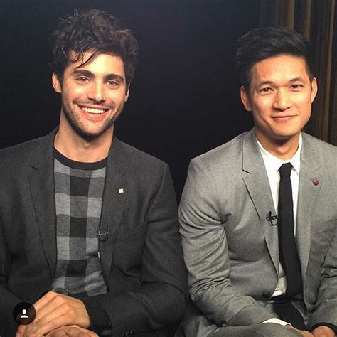 Two Men Sitting Next To Each Other In Front Of A Dark Background One