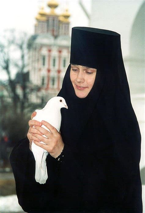 A Woman Holding A White Bird In Her Right Hand And Wearing A Black Hijab