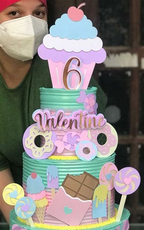 A Woman Wearing A Face Mask And Holding A Cake With The Number Six On It