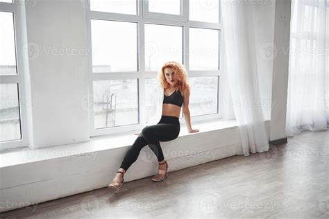 On The Windowsill Attractive Redhead Woman Posing In The Spacey Room Near The Window 8681306