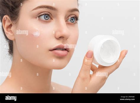Young Beautiful Woman Applies Cream To Her Face Close Up Long Hair Big Blue Eyes And Clear