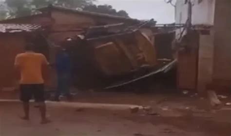 Trator transportado em caminhão cai de carroceria e atinge casa