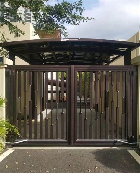 An Open Gate In Front Of A Building With Palm Trees And Bushes Around