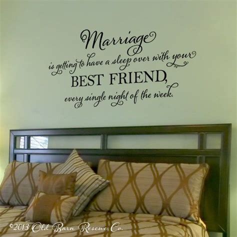 A Bedroom With A Bed Pillows And Wall Decal That Says Marriage Is