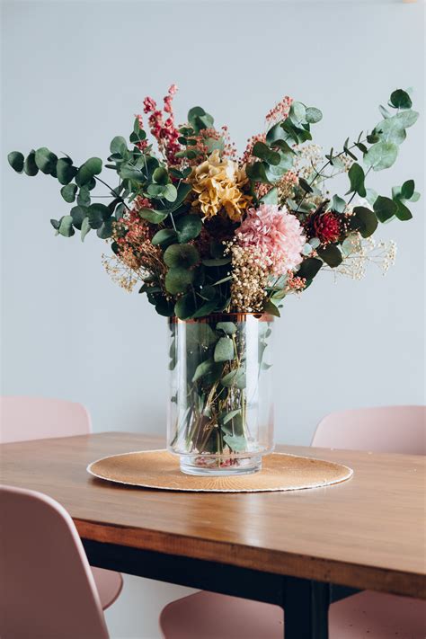 Jarrón de cristal elegante con flores rosas y granates