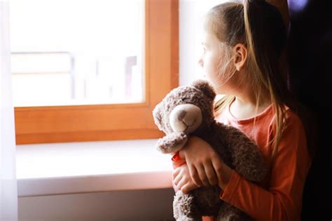 Hermosa niña sonriendo y mirando por la ventana un niño mira por la