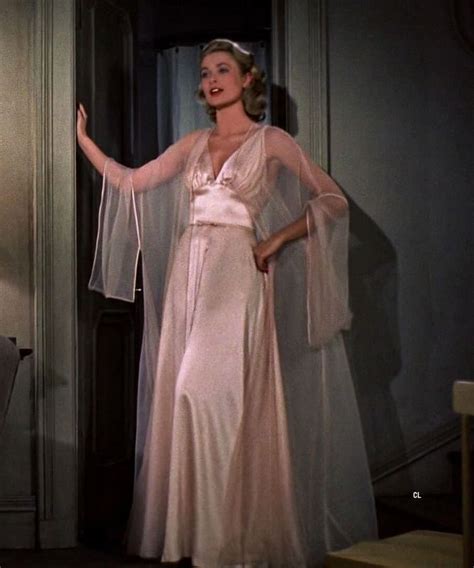 A Woman In A Pink Dress Standing Next To A Door With A Veil On Her Head
