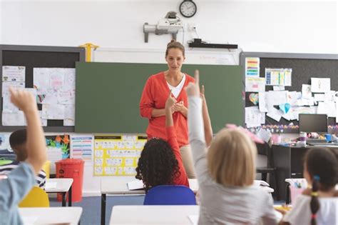 Vista traseira de crianças em idade escolar levantando a mão para