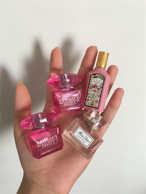 Three Small Bottles Of Perfume In The Palm Of Someone S Hand One Pink