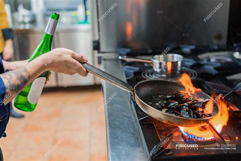 Chef Cooking With Flame In Frying Pan Crop Work Stock Photo