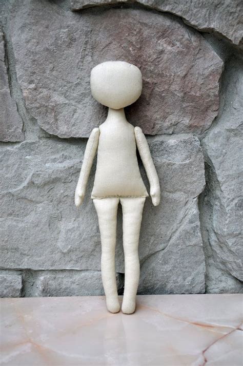 A Small White Doll Standing In Front Of A Stone Wall With Its Head
