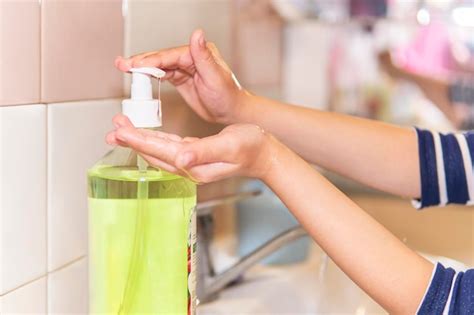 El niño se lava las manos con jabón líquido de una botella concepto de