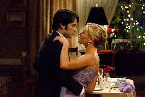 A Man In A Tuxedo And Woman In A Purple Dress Hugging Each Other