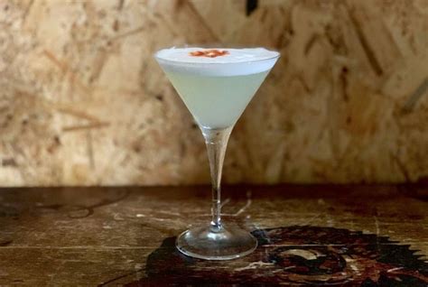 A Martini Glass With An Orange Garnish On The Rim Sitting On A Table