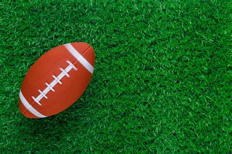 Campo de deportes de hierba verde con pelota de fútbol americano
