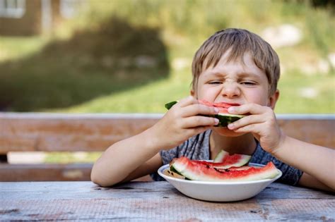 Lindo niño caucásico comiendo sandía en el campo Foto Premium