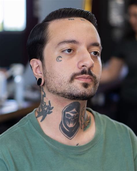 A Man With Tattoos On His Neck Stares Into The Distance