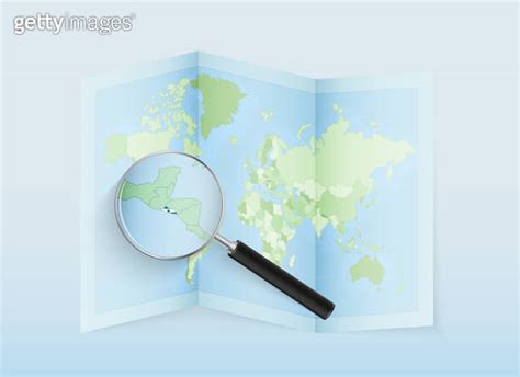 A Folded World Map With A Magnifying Lens Pointing Towards El Salvador