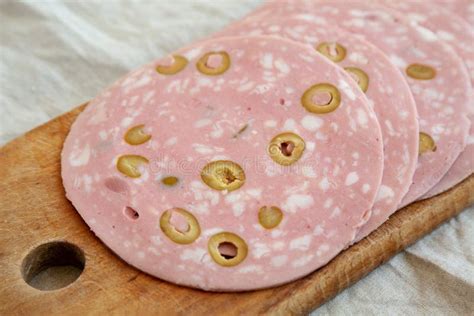 Organic Sliced Mortadella Sausage With Olives On A Rustic Wooden Board