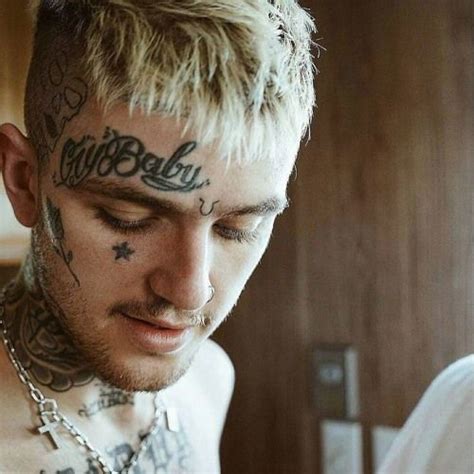 A Man With Tattoos On His Face And Chest Is Looking Down At The Camera