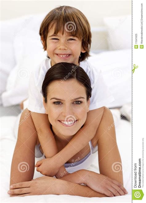 Mother And Son Laying On Bed Smiling At The Camera Stock Photo Image