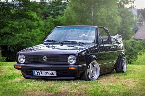A Black Car Parked On Top Of A Lush Green Field