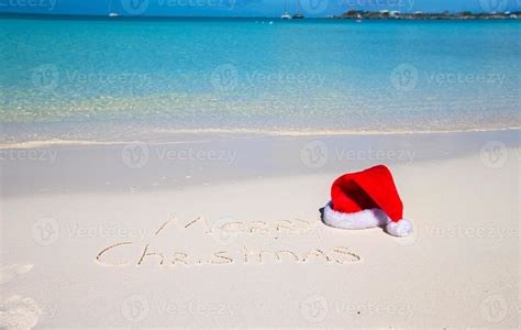Merry Christmas Written On Tropical Beach White Sand With Xmas Hat