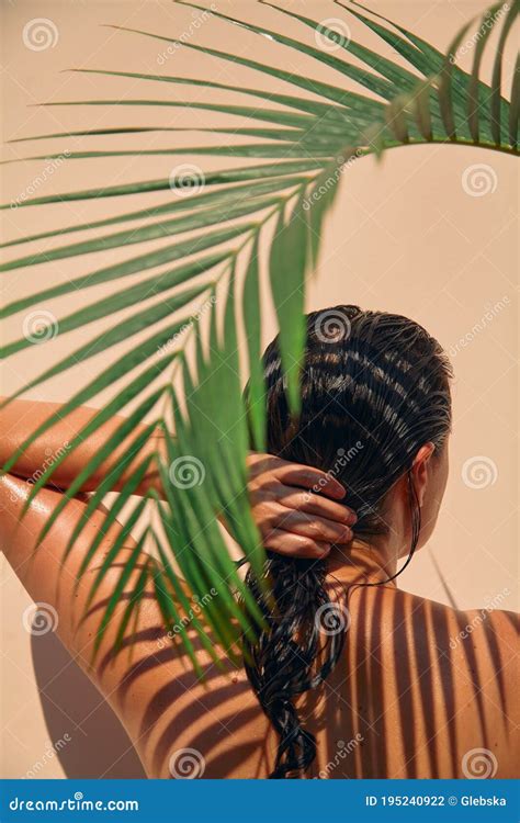 Mujer Desnuda Se Alisa El Pelo Bajo La Rama De La Palma Foto De Archivo