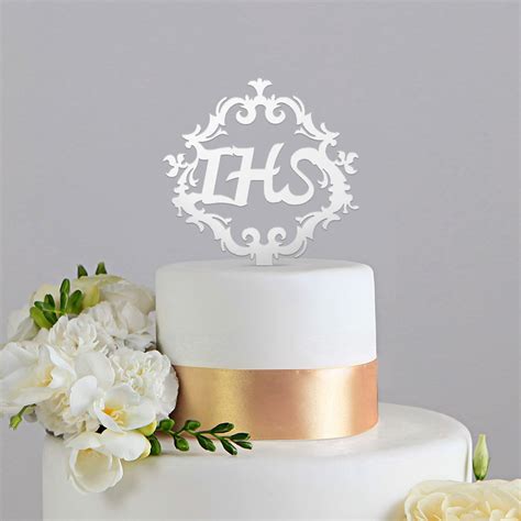 A White Cake With Gold Ribbon And Flowers On Top