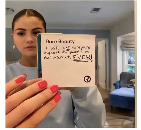 A Woman Holding Up A Note That Says Rare Beauty