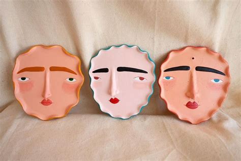 Three Plates With Faces Painted On Them Sitting Next To Each Other In