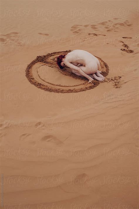 Naked Redhead Girl Drawing Sign On Sand With Her Hands By Stocksy