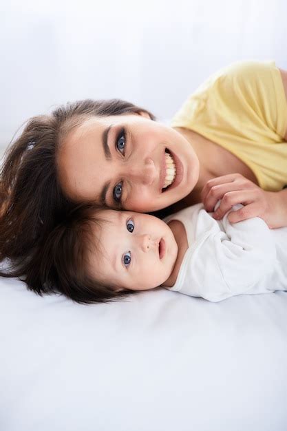 La mère embrasse sa fille et se couche sur le lit Photo Gratuite