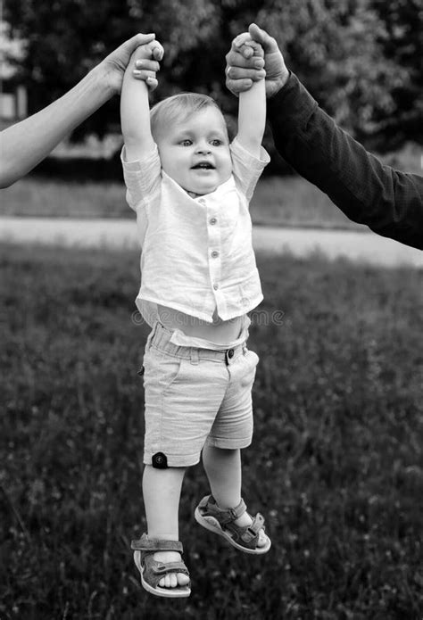 Niñito Jugando Al Aire Libre En El Césped Padre Y Madre Sosteniendo Manos Del Bebé Foto De