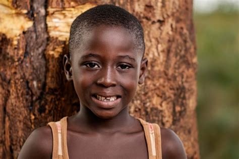 Niño africano de primer plano posando cerca de árbol Foto Premium