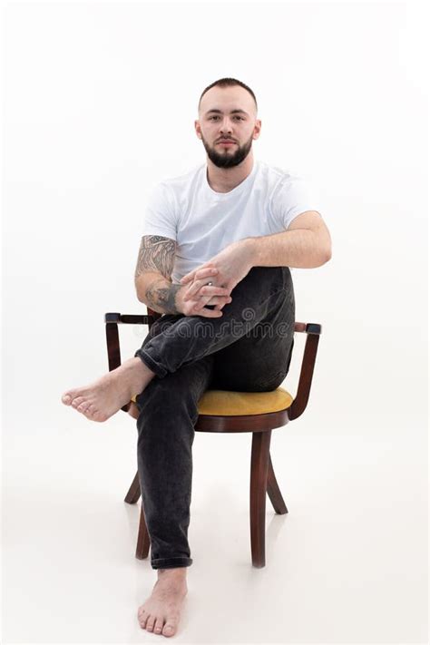 Vertical Portrait Tattooed Handsome Brunet Confident Bearded Barefoot Man Sitting On Chair