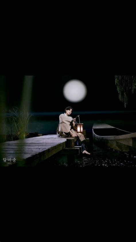 A Woman Sitting On A Dock Holding A Lantern